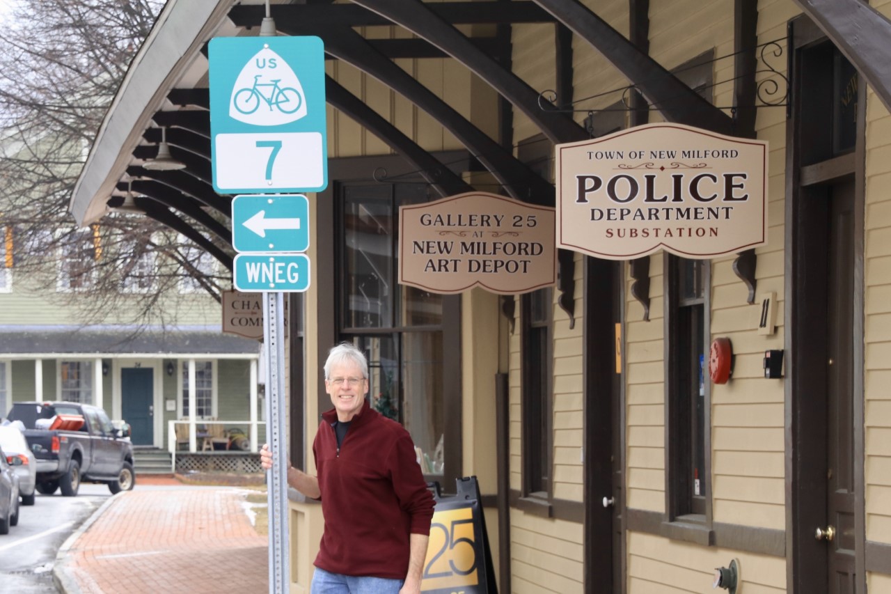 Cyclist helps to install directional signs on Route 7 bike route