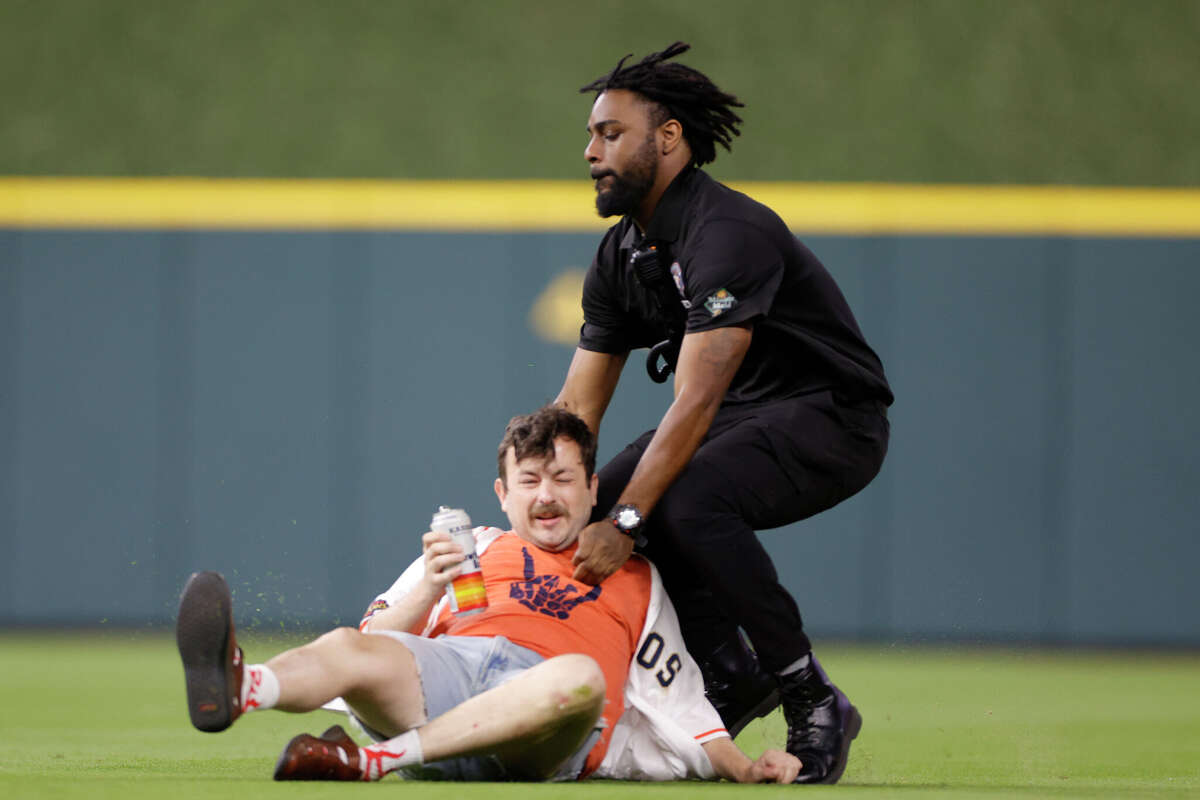 Fan in jorts, holding beer runs on field during Astros-Rangers game