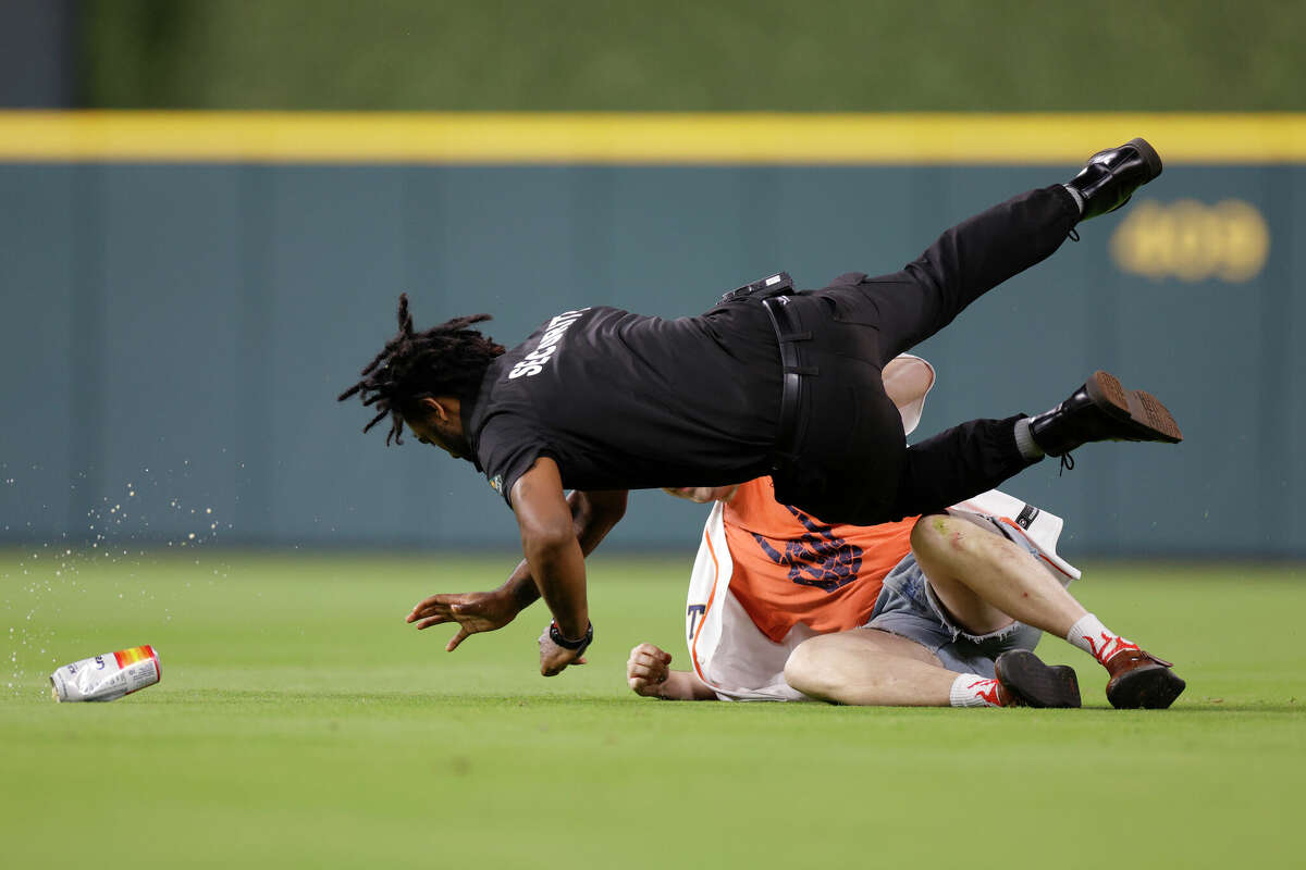 Fan in jorts, holding beer runs on field during Astros-Rangers game