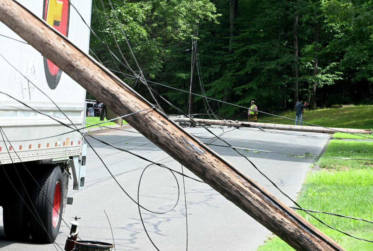 Uprooted utility poles trap truck driver after Vernon accident