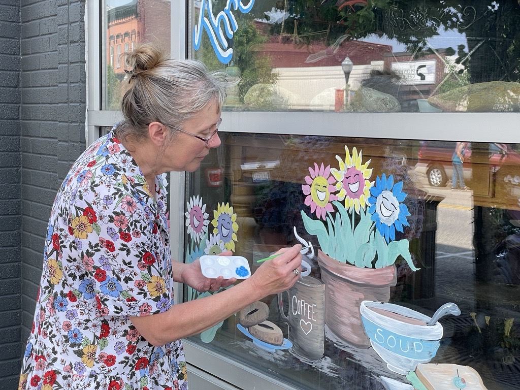 Baker Paula Beilfuss of Three Girls Bakery touches up window art