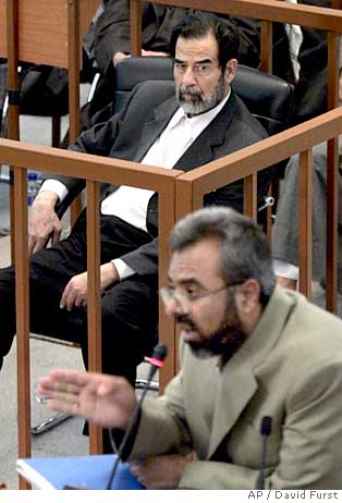 Hussein faces victims amid shouts, chaos / As trial's first witnesses ...