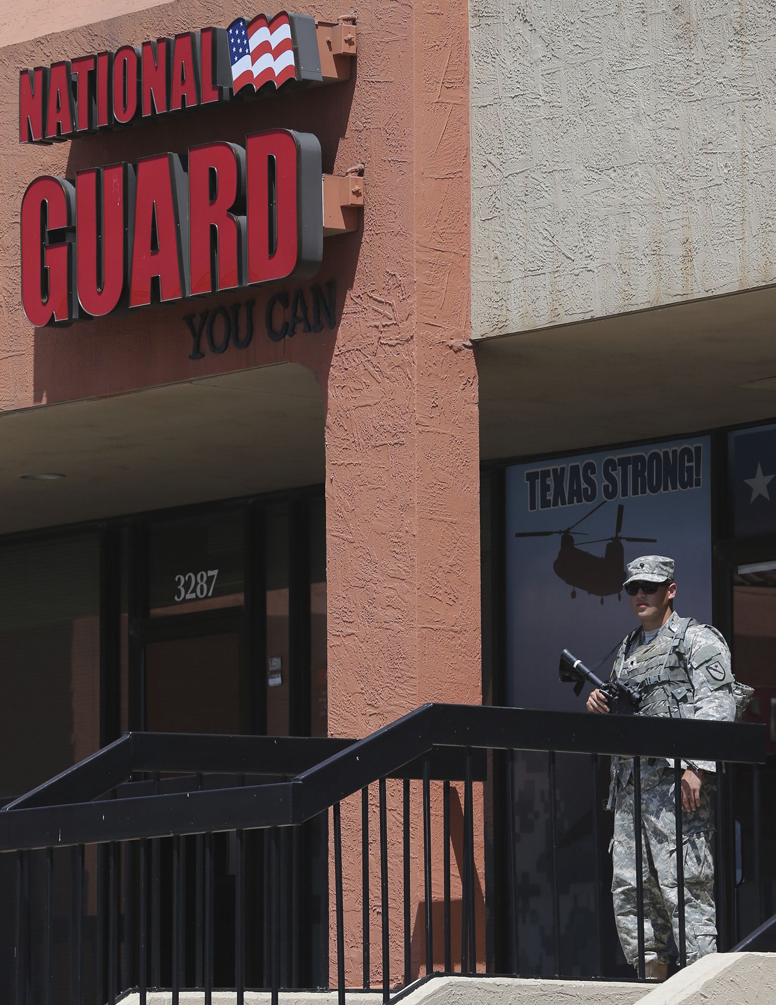 Armed civilians, national guard troops watch recruiting centers