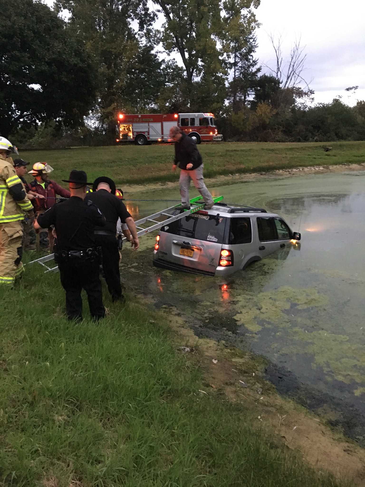 Driver atop SUV rescued from pond
