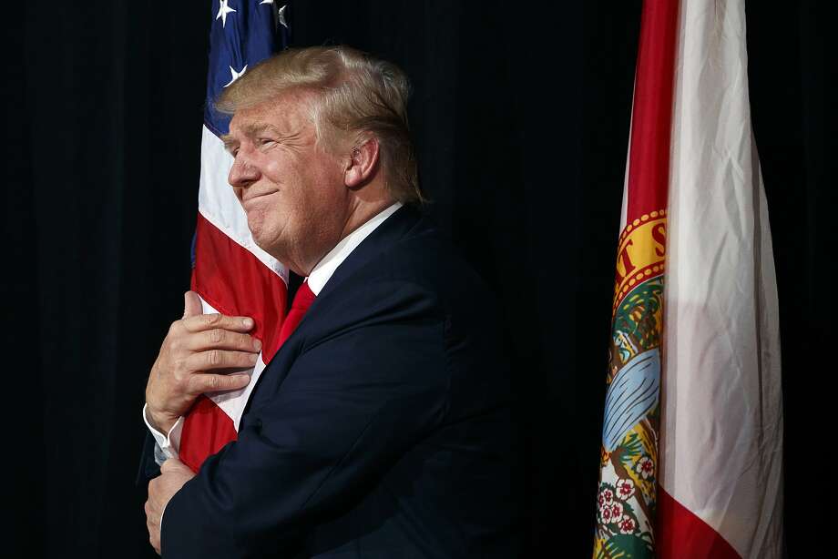 Trump awkwardly hugs a flag after defending immigration policies - SFGate