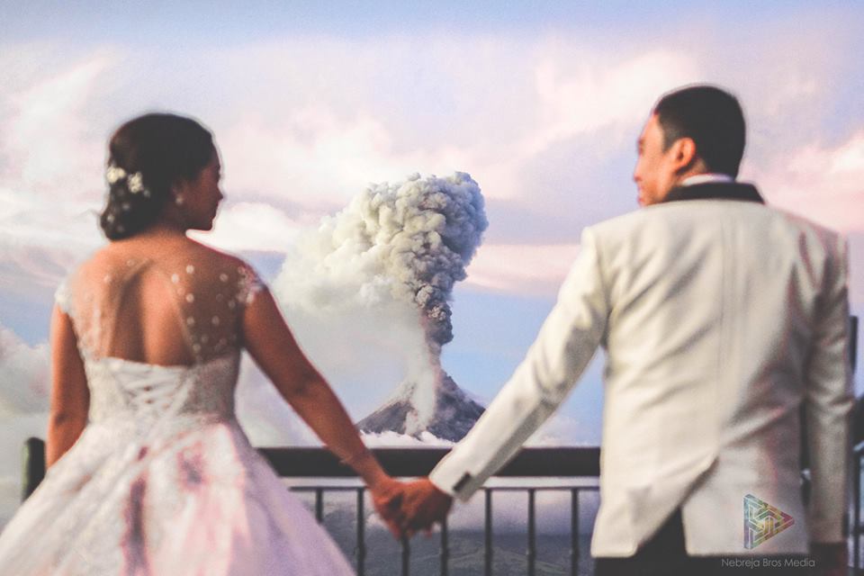 Couple poses for stunning wedding photos in front of erupting volcano